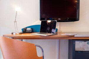 Uma mesa com um laptop, um telefone e uma revista.