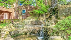 Um deck de madeira com uma parede de pedra e uma pequena cascata.