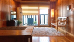Interior de cabana de madeira com mesa de jantar, bancos e lareira.