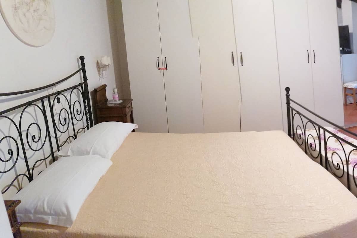 Quarto com cama, cadeira, televisão e guarda-roupa.