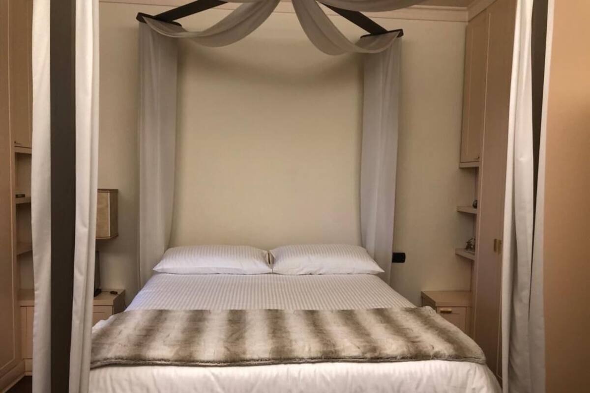 Quarto com cama de dossel, roupa de cama branca e manta de pele.