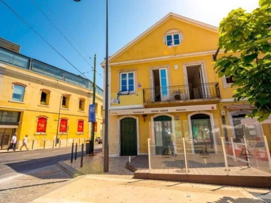 Um edifício amarelo com varanda e fachada comercial.