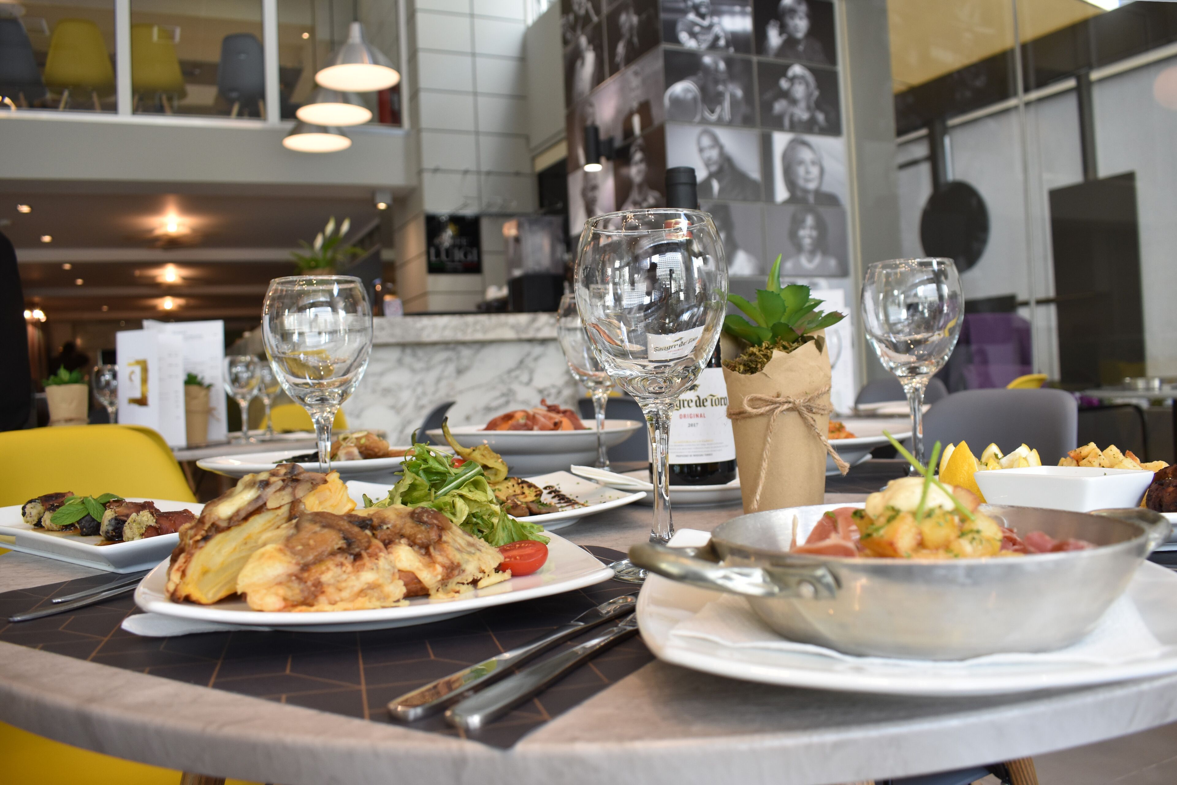 Uma mesa de jantar com pratos de comida, copos de vinho e talheres.