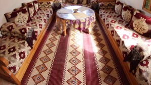 Um quarto com piso estampado, uma mesa redonda com toalha de mesa estampada e um sofá com almofadas estampadas.