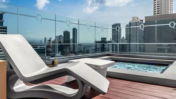 Terraço no telhado com piscina, espreguiçadeiras e vista para o horizonte da cidade.