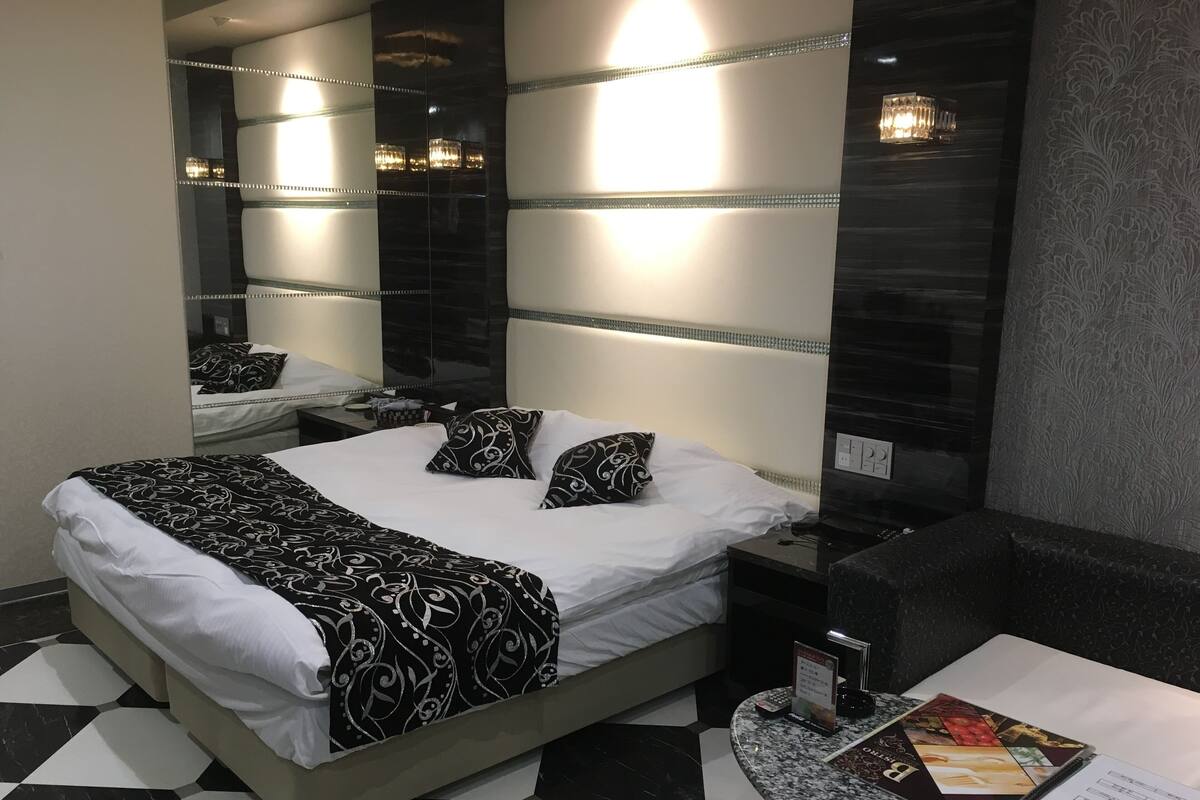 Quarto de hotel com cama, mesa de cabeceira, área de estar e piso de mármore.
