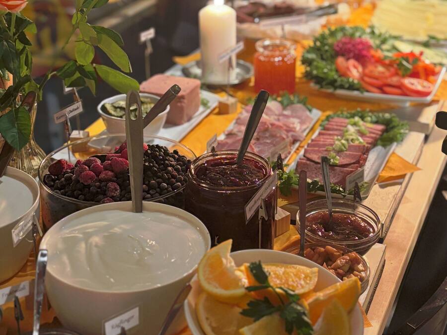 Buffet com diversos tipos de comida, incluindo frutas, carnes e acompanhamentos.