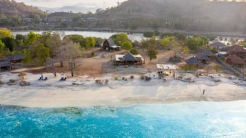 Uma área costeira com praia, um pequeno povoado com casas e um corpo d'água ao fundo.