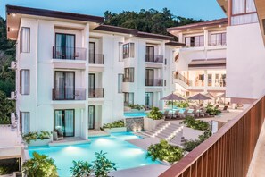 Um hotel com vários andares, piscina, área de estar externa e varandas.
