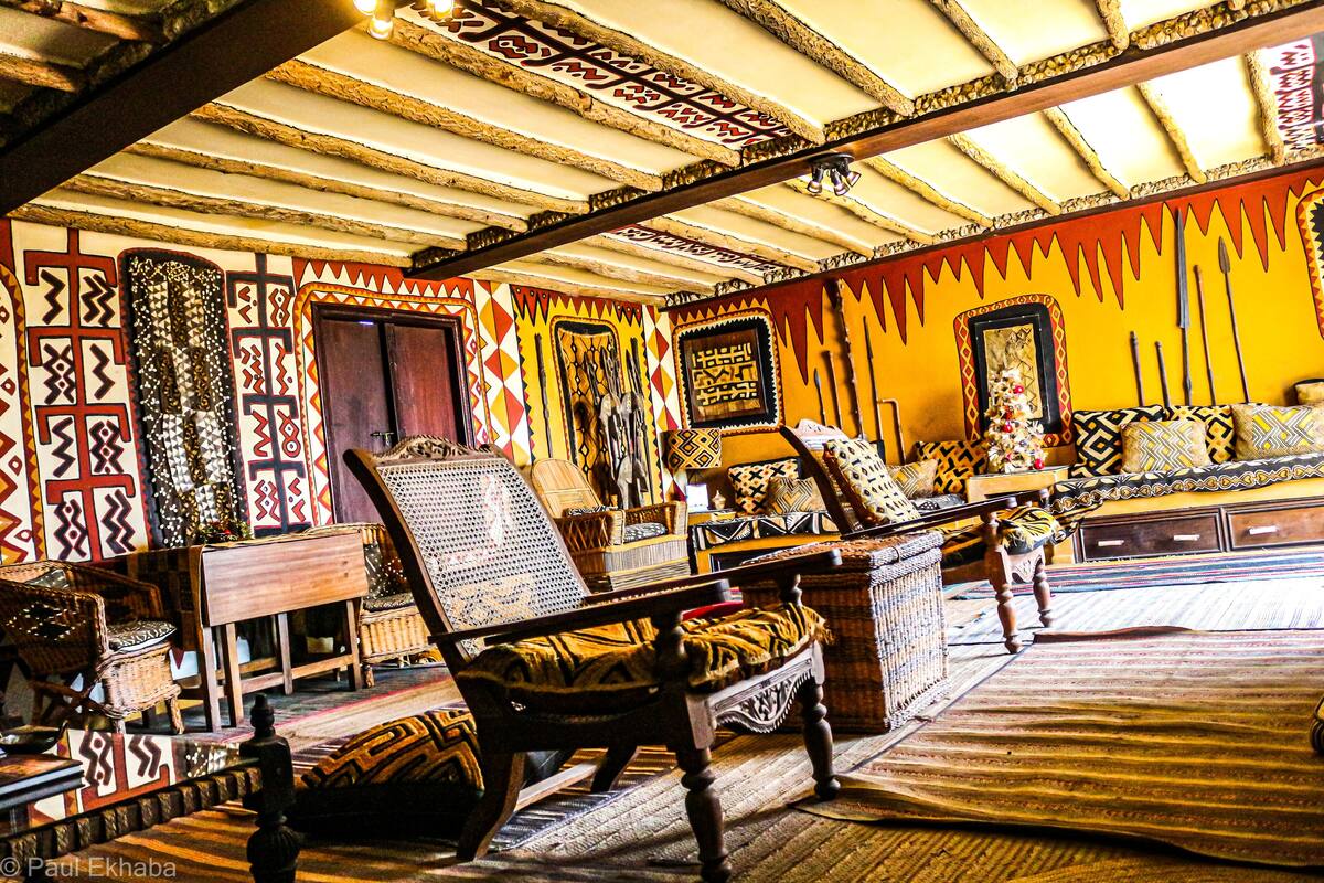 Quarto tradicional com paredes estampadas, teto de madeira e diversos móveis de tear.
