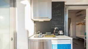 Uma cozinha moderna com eletrodomésticos de aço inoxidável, uma lousa com uma receita e vista para o quarto adjacente.