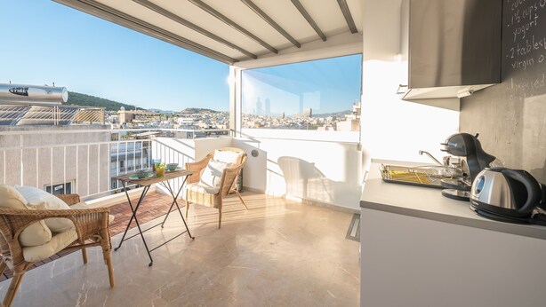 Varanda com vista para a cidade, mobiliário de vime e máquina de café.