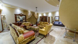 Uma sala de estar espaçosa com um sofá grande, poltronas, uma mesa de centro e um lustre.