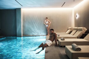 Área de piscina com espreguiçadeiras e uma pessoa próxima à piscina.