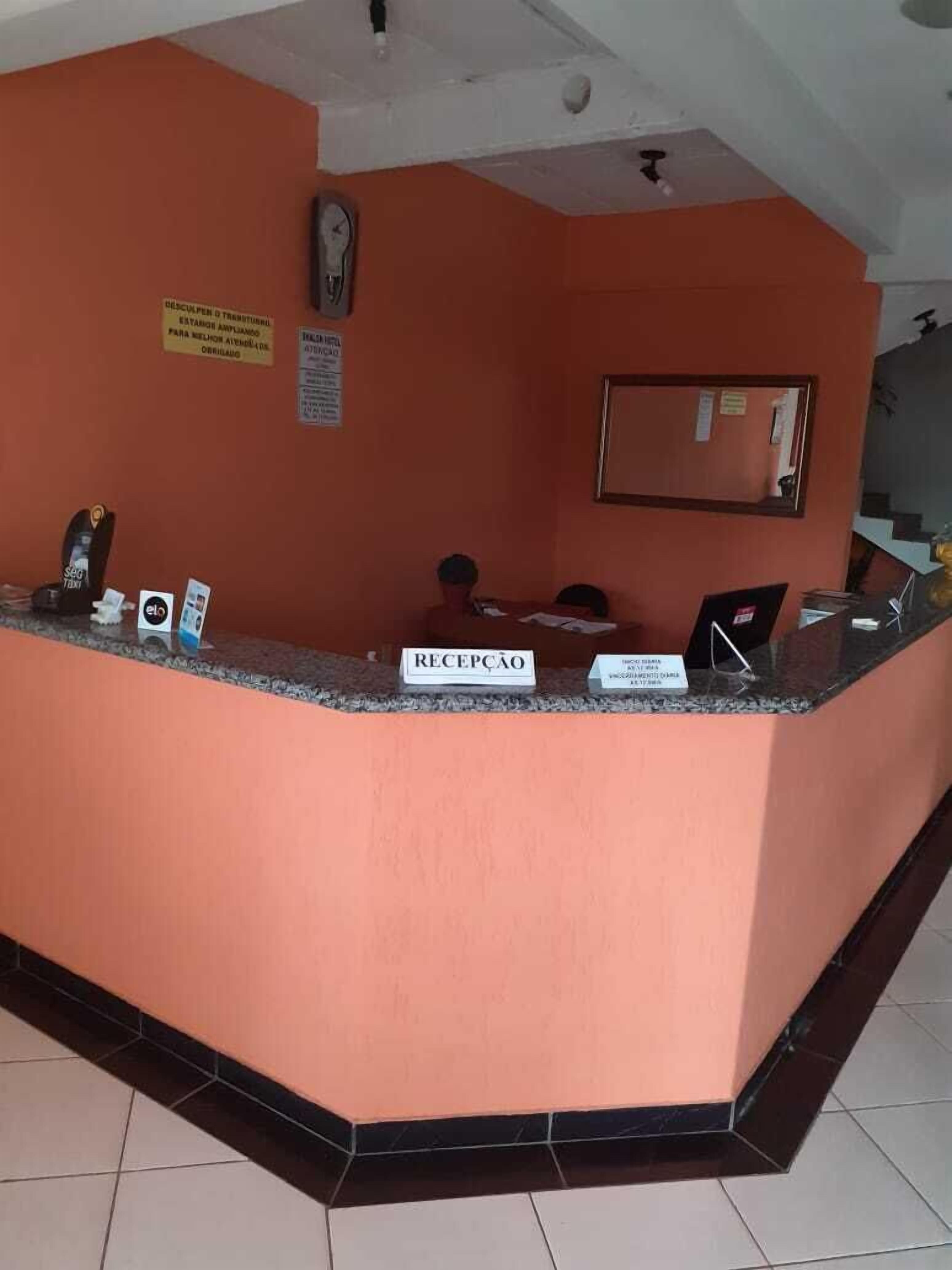 Uma mesa de recepção com uma placa que diz 'RECEPCAO' no saguão de um hotel.