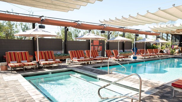 Piscina com espreguiçadeiras e guarda-sóis.