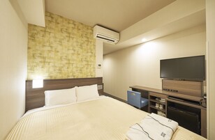 Quarto de hotel com uma cama grande, televisão de tela plana, escrivaninha com cadeira e ar condicionado.
