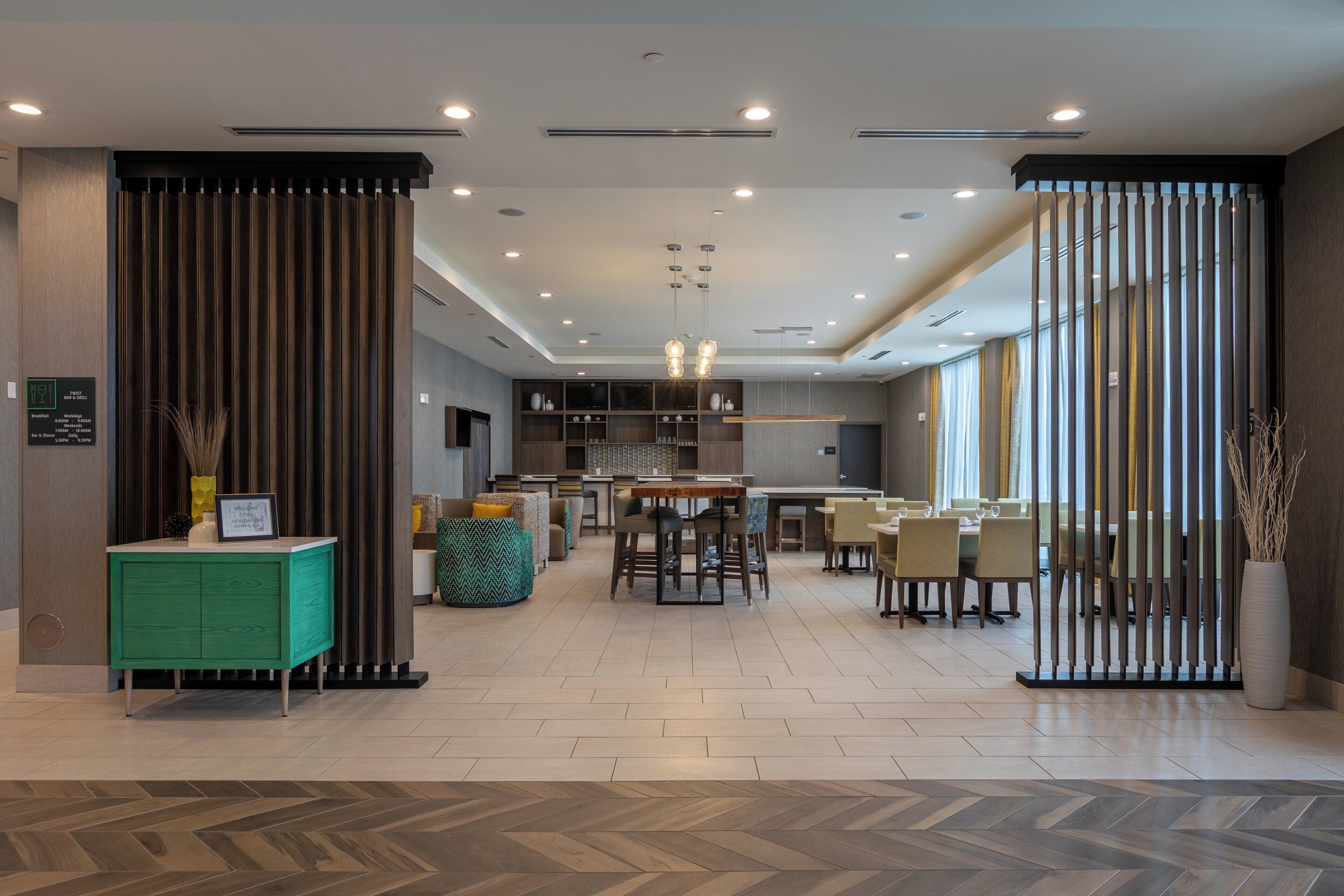 Um hall de hotel moderno com área de bar, assentos e balcão de recepção.