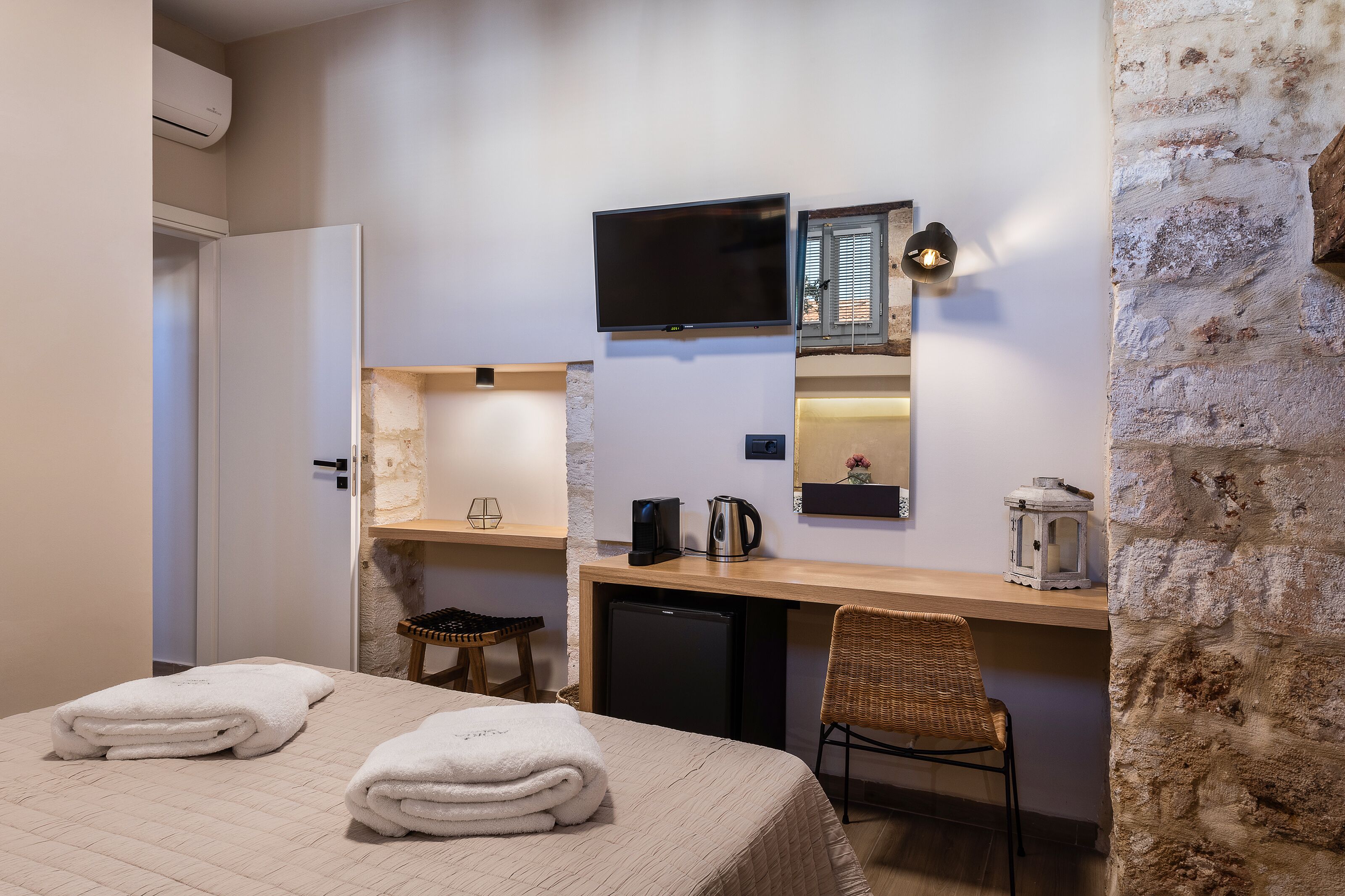 Quarto de hotel com cama, mesa de escritório com computador, televisão e uma pequena área de estar.