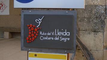 Um sinal para 'Portal del Montsec' com o símbolo de uma montanha e um círculo vermelho. Abaixo, um sinal para 'Ruta del Vi Lleida Costers del Segre' com um círculo vermelho e uma linha branca. Na parte inferior, um sinal para 'Centres BTT' com o símbolo de uma bicicleta e informações sobre horários de funcionamento.