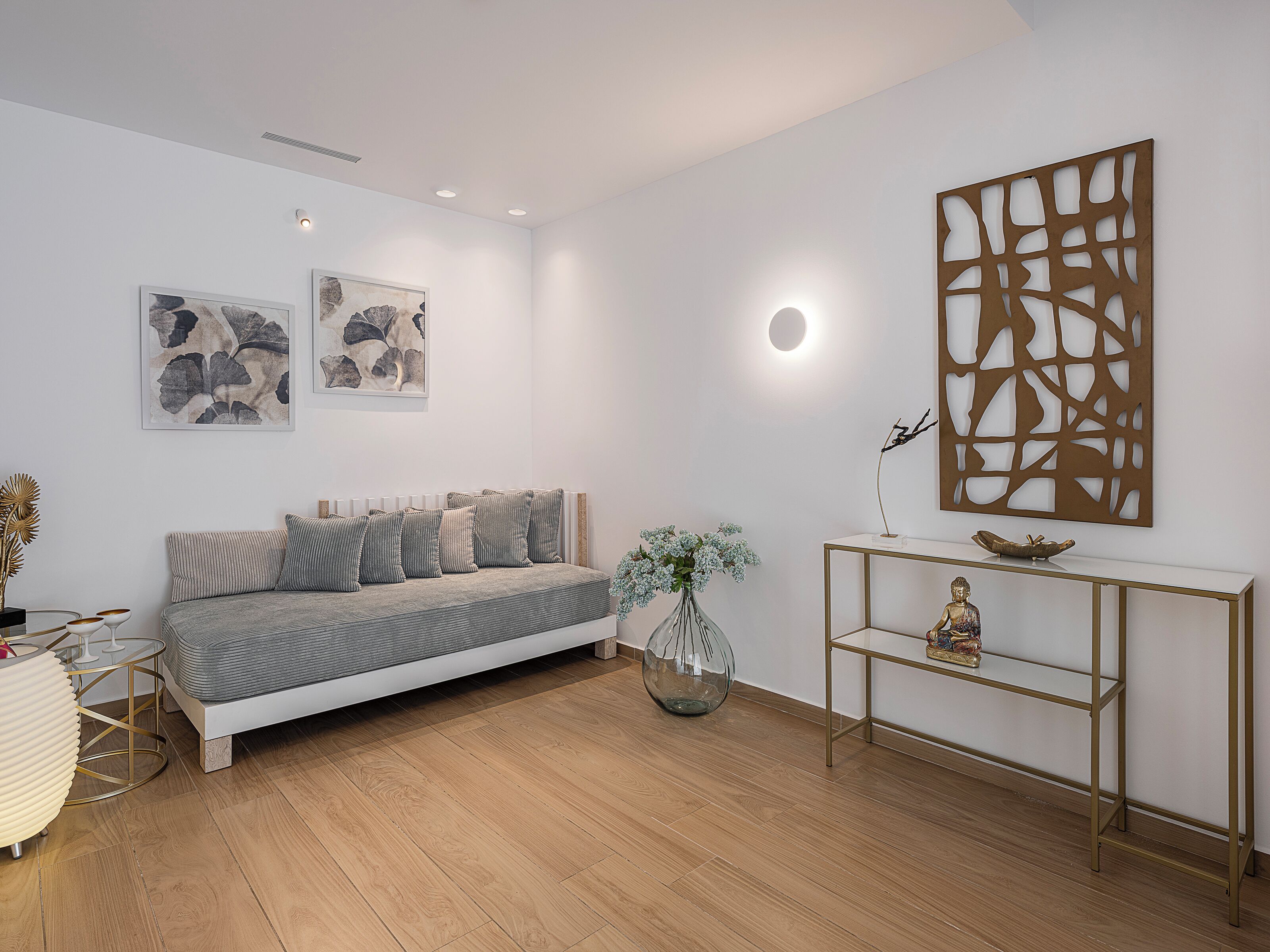 Quarto moderno com cama, mesa de apoio e obras de arte na parede.