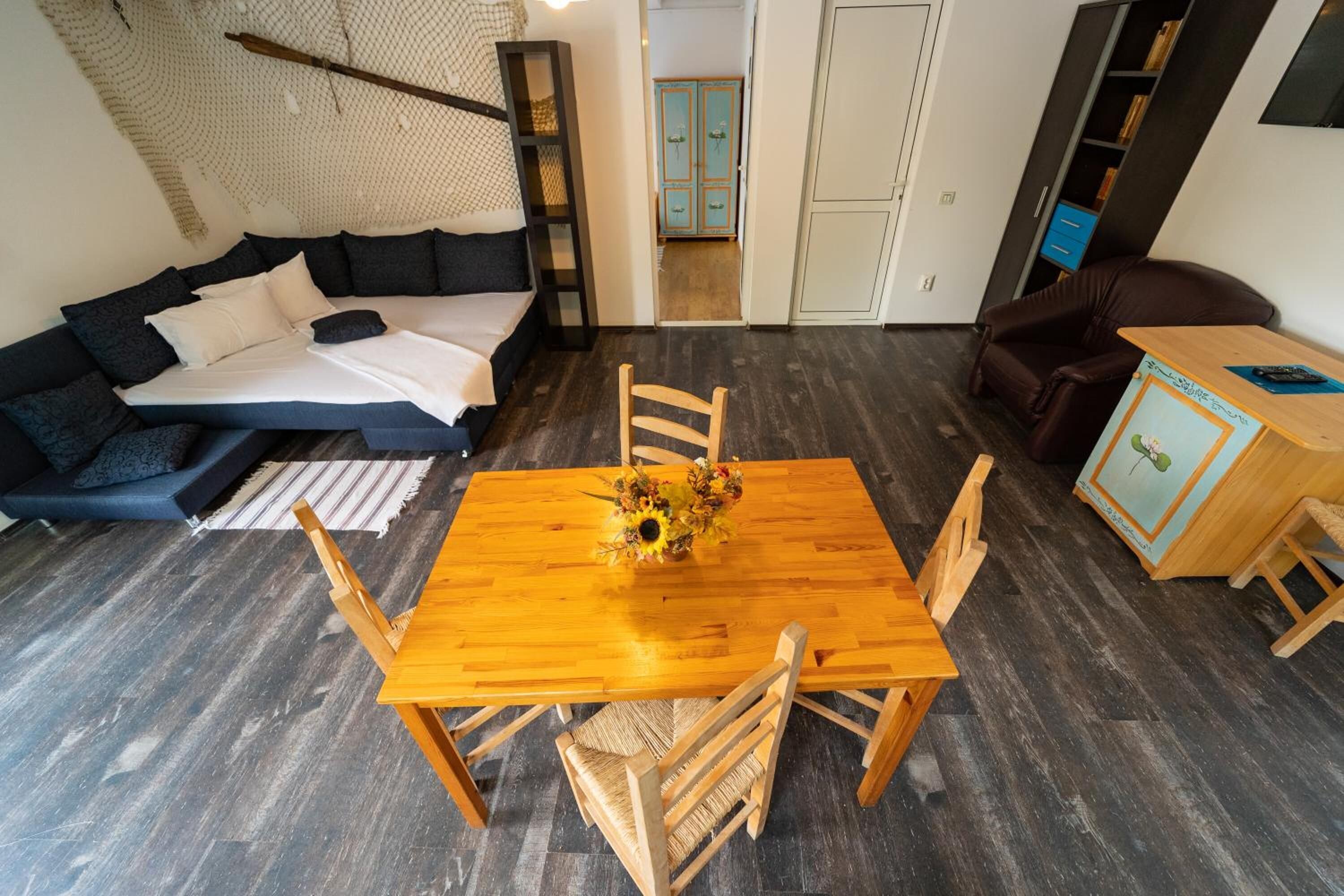 Uma sala de estar acolhedora com um sofá, uma mesa de jantar de madeira com cadeiras, um pequeno armário e uma estante.