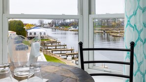 Uma mesa com copos de vidro transparente e vista para uma área de cais através de grandes janelas.