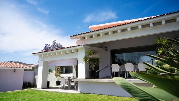 Uma casa moderna com um pátio, paredes brancas e telhado de telhas vermelhas.