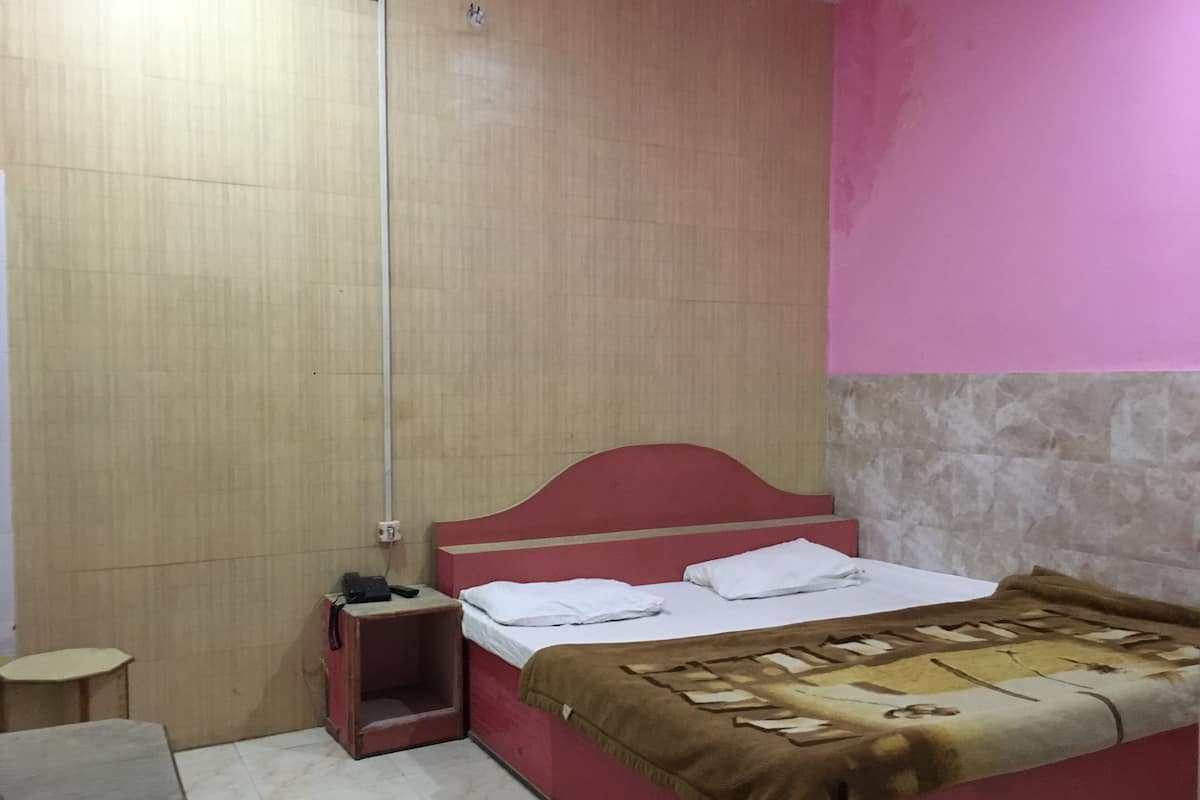 Um quarto com cama, uma mesinha e uma mesa de cabeceira.