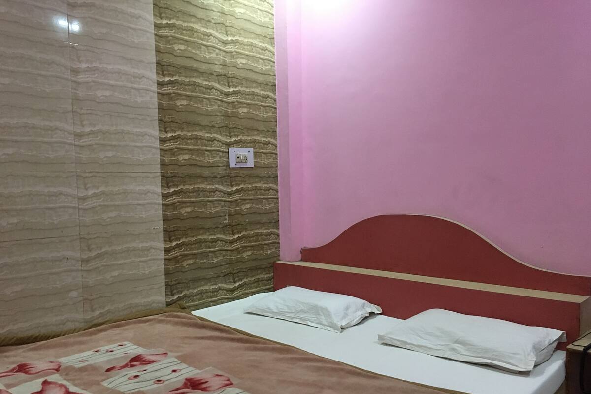 Quarto com cama, parede com textura, tomada e parede rosa.