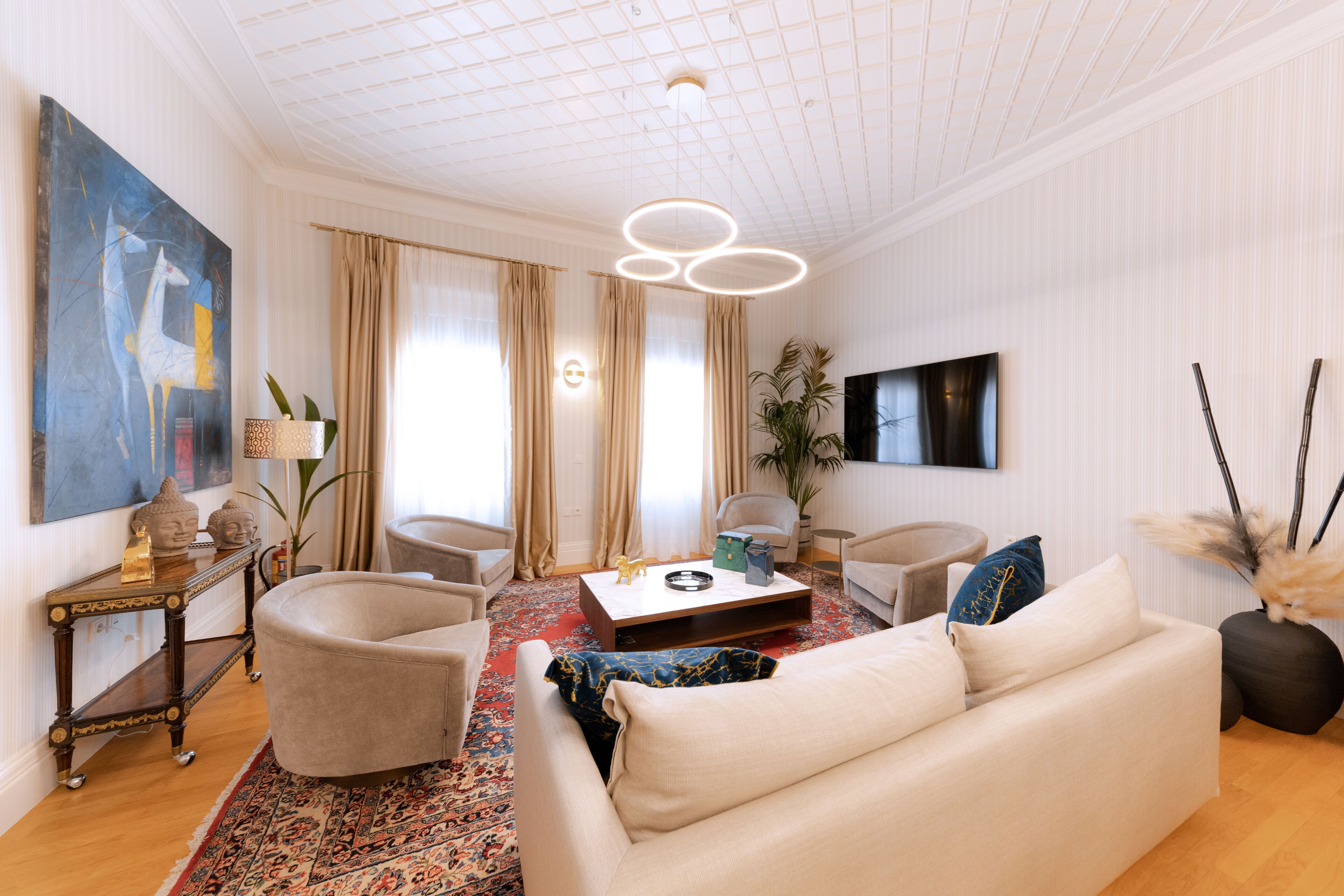 Uma sala de estar moderna com um sofá, cadeiras, uma mesa de centro e um quadro grande na parede.