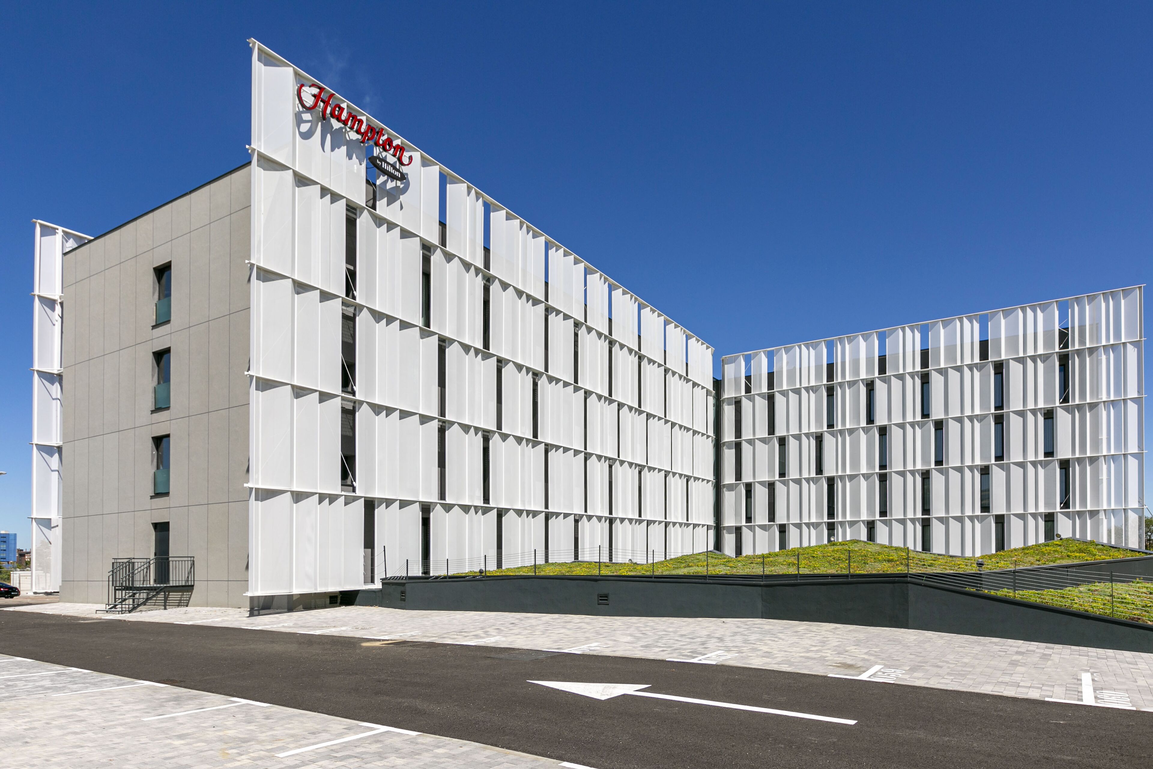 Um edifício moderno com uma placa chamativa que diz "Hampton Inn".