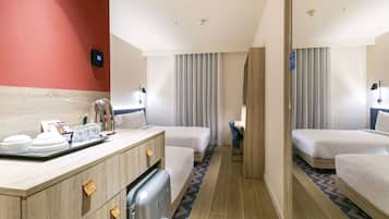 Quarto de hotel com duas camas, uma mesa com bandeja de itens de café da manhã, minibar e área de chuveiro.