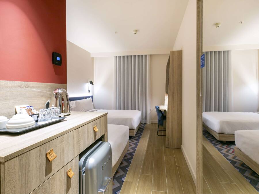 Quarto de hotel com duas camas, uma mesa com bandeja de itens de café da manhã, minibar e área de chuveiro.