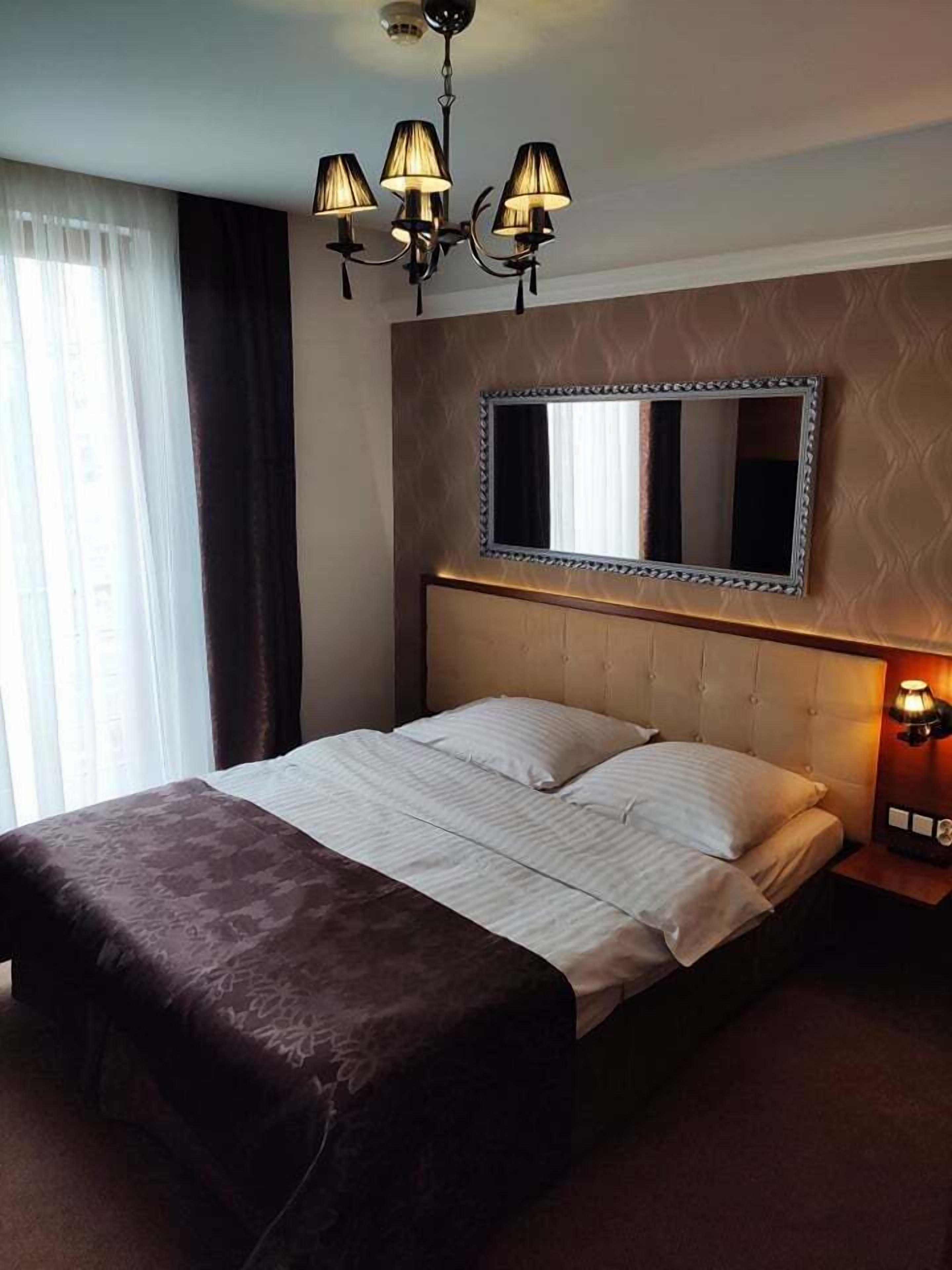 Quarto de hotel com cama, um espelho grande e um candelabro.