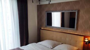 Quarto de hotel com cama, um espelho grande e um candelabro.