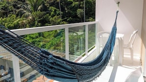 Uma rede numa varanda com vista para um verde exuberante.