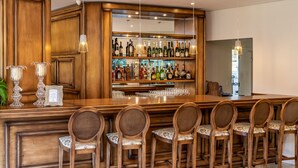 Uma área de bar com balcão de madeira, várias garrafas de bebidas e cadeiras combinando.