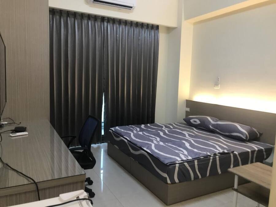 Quarto de hotel com uma cama, uma escrivaninha e uma cadeira.