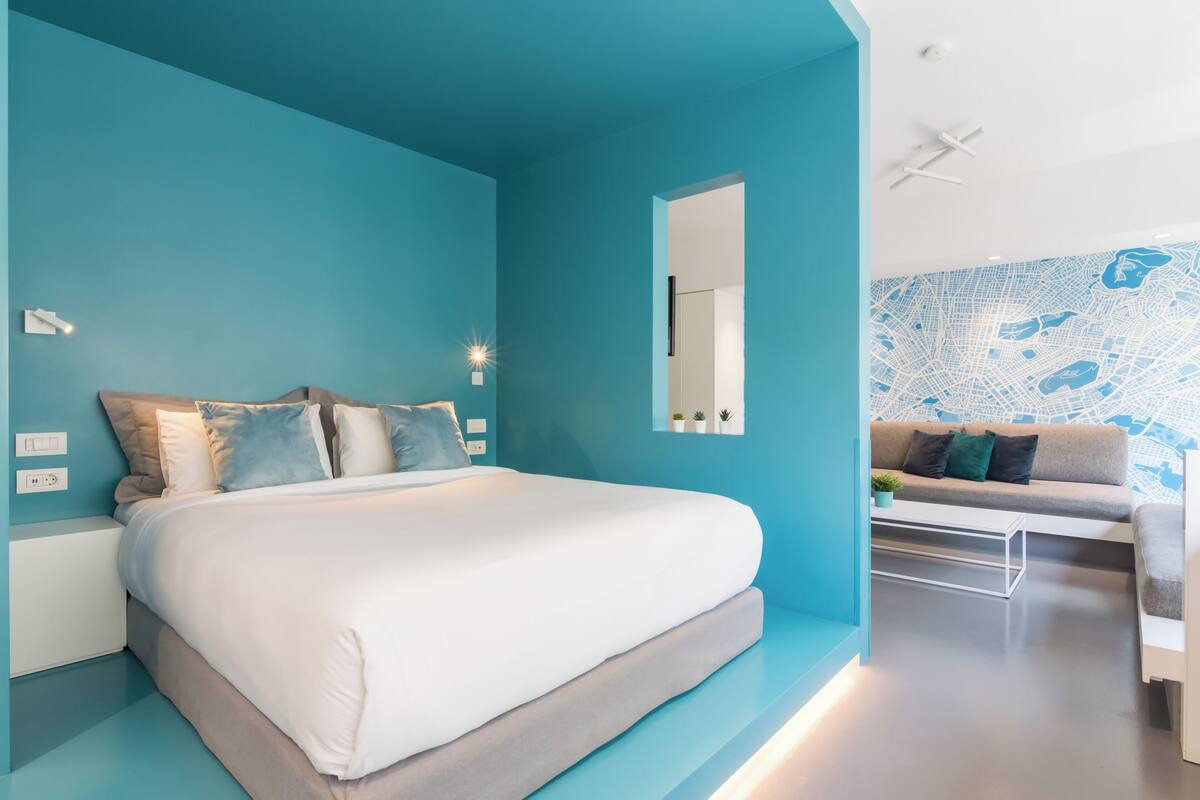 Quarto moderno com uma cama grande, um sofá e um mural de mapa.