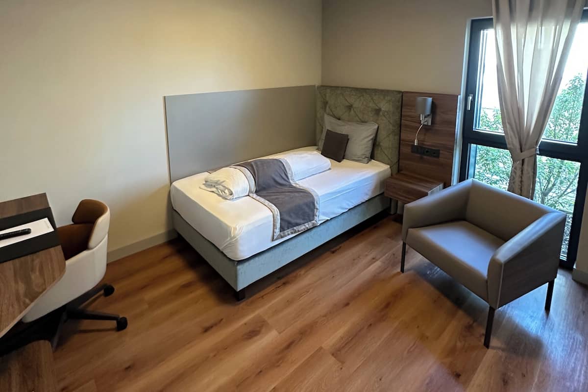 Quarto moderno com cama, escrivaninha, cadeira e janela com cortinas.