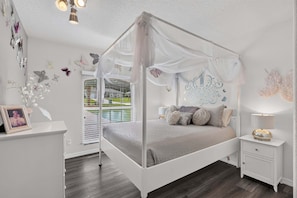 Quarto com cama de dossel, paredes brancas e janela com persianas.