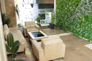 Um hall de entrada com um conjunto de sofás, uma mesa de centro e plantas em vasos.
