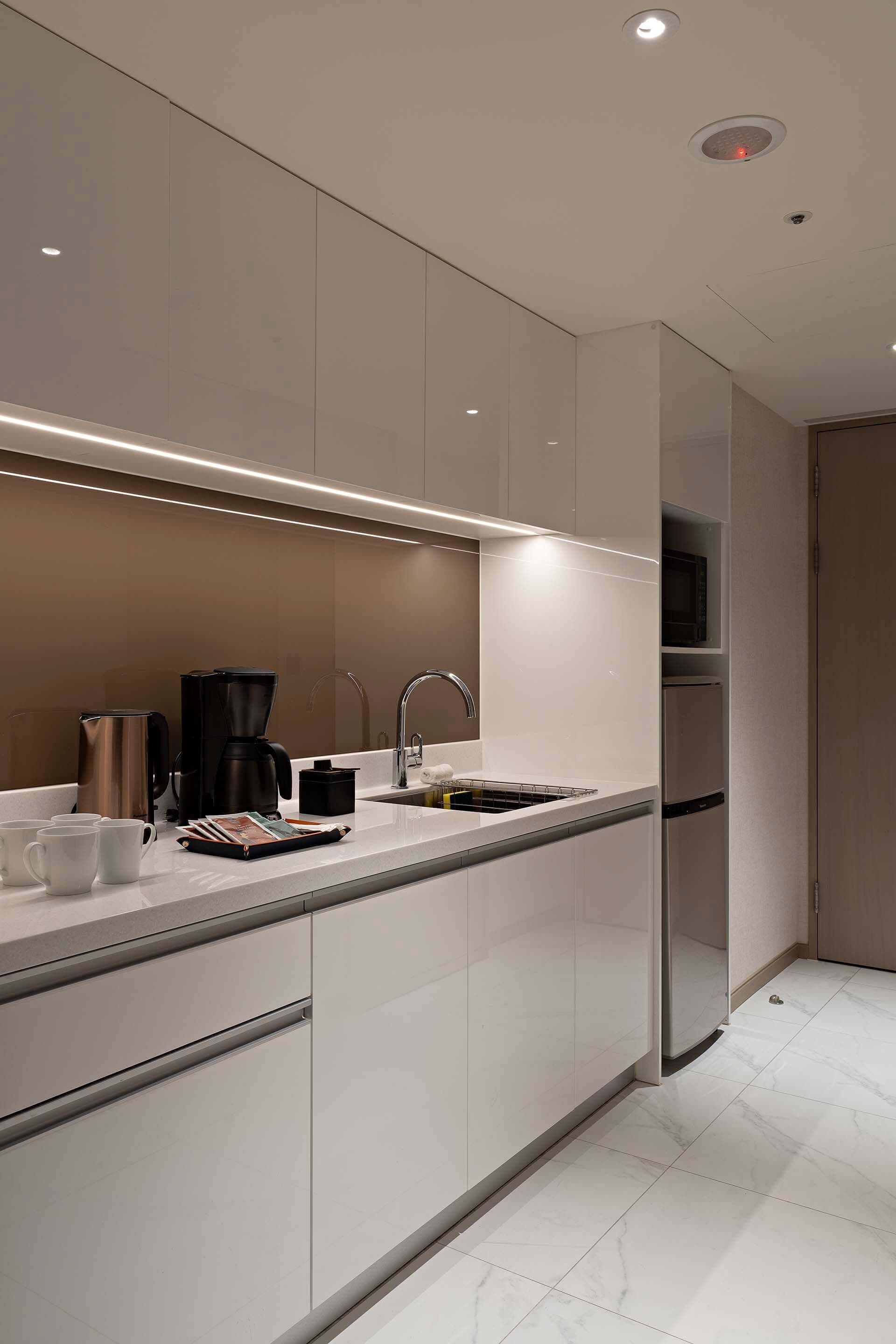 Uma cozinha moderna com design elegante, apresentando uma pia de aço inoxidável, uma cafeteira e um micro-ondas.