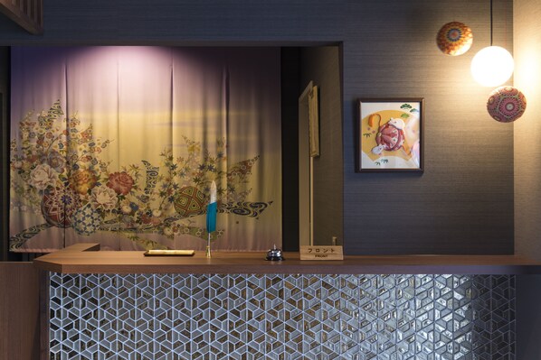 Balcão de recepção com um painel de cortina floral, uma obra de arte emoldurada e uma parede estampada.