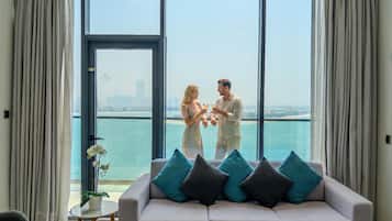 Uma sala de estar moderna com uma janela ampla que oferece vista para um corpo d'água e o horizonte da cidade.