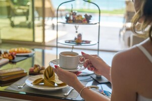 Uma pessoa segurando uma xícara de café com uma bandeja de doces em um café.