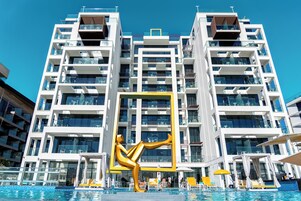 Um hotel moderno de vários andares com área de piscina e uma grande escultura dourada.