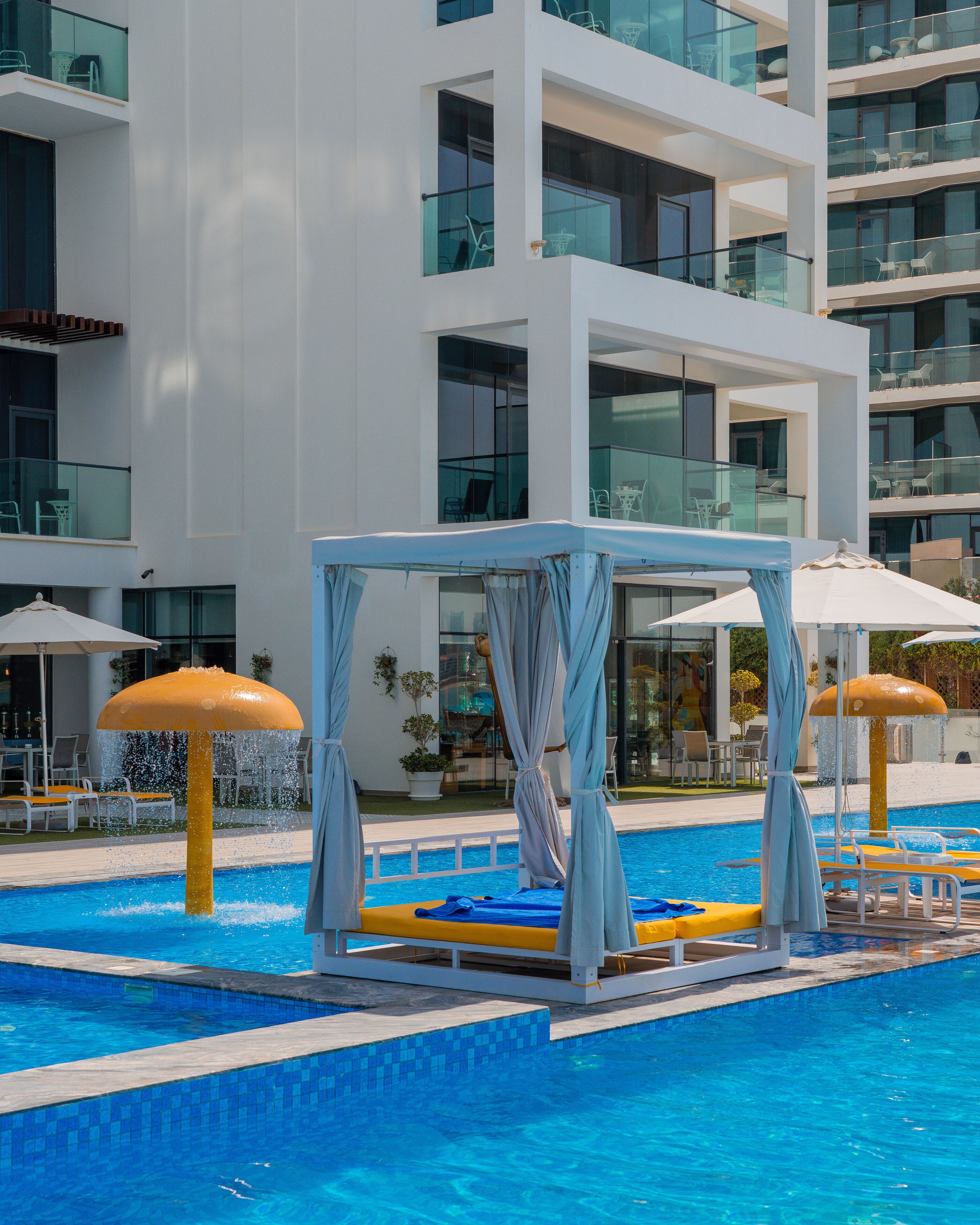 Uma piscina com cabana, espreguiçadeiras e guarda-sóis.