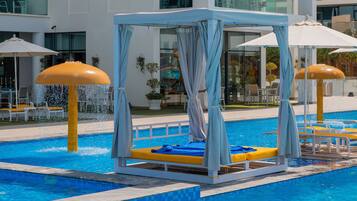 Uma piscina com cabana, espreguiçadeiras e guarda-sóis.